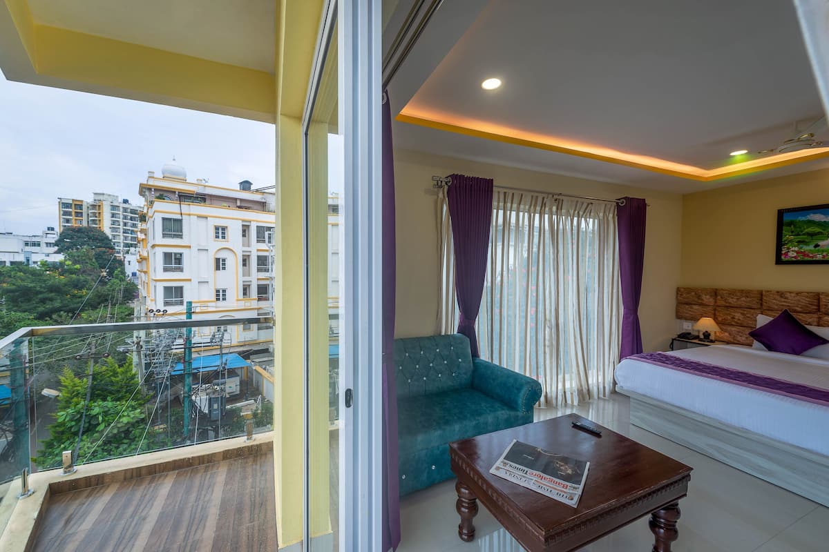 Varanda com vista para edifícios, um sofá, uma cama e uma mesa com uma revista.