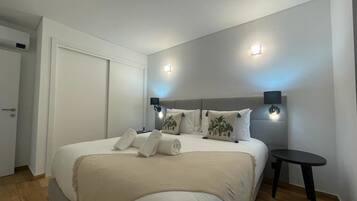 Quarto moderno com cama grande, abajures e uma mesinha.