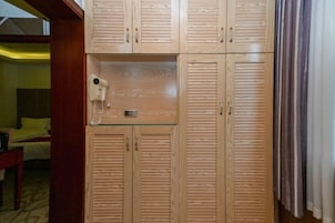 Quarto de hotel com armários de madeira, secador de cabelo e cama com roupa de cama amarela.