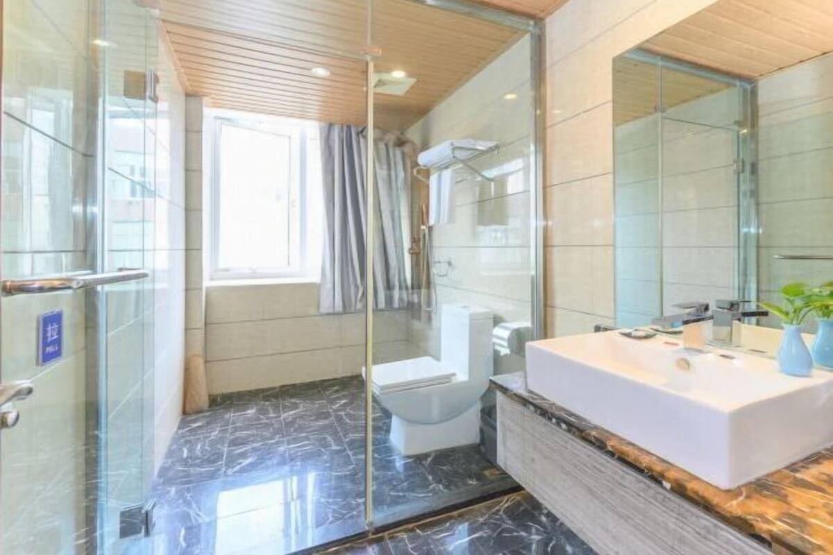 Um banheiro moderno com box de vidro, um espelho grande e piso de mármore.