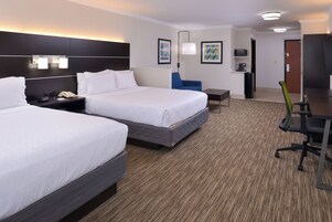 Quarto de hotel com duas camas, uma escrivaninha, uma cadeira e uma televisão.