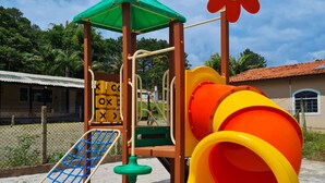 Um parquinho com escorrega, rede de escalada e estrutura decorada com flores.