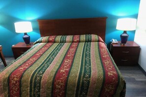 Uma cama com colcha listrada, duas mesas de cabeceira com abajures e uma parede azul.