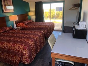 Quarto de hotel com duas camas, uma escrivaninha e vista para o exterior.