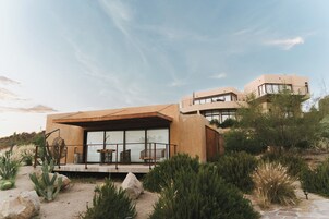 Uma casa moderna com telhado plano, grandes janelas e um espaço de varanda com móveis de exterior.