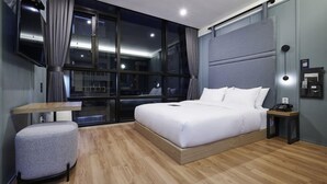 Quarto de hotel moderno com uma cama grande, uma escrivaninha e uma cadeira.