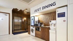 Cozinha moderna com um letreiro 'JUST DINING', máquina de lavar, geladeira e elevador.
