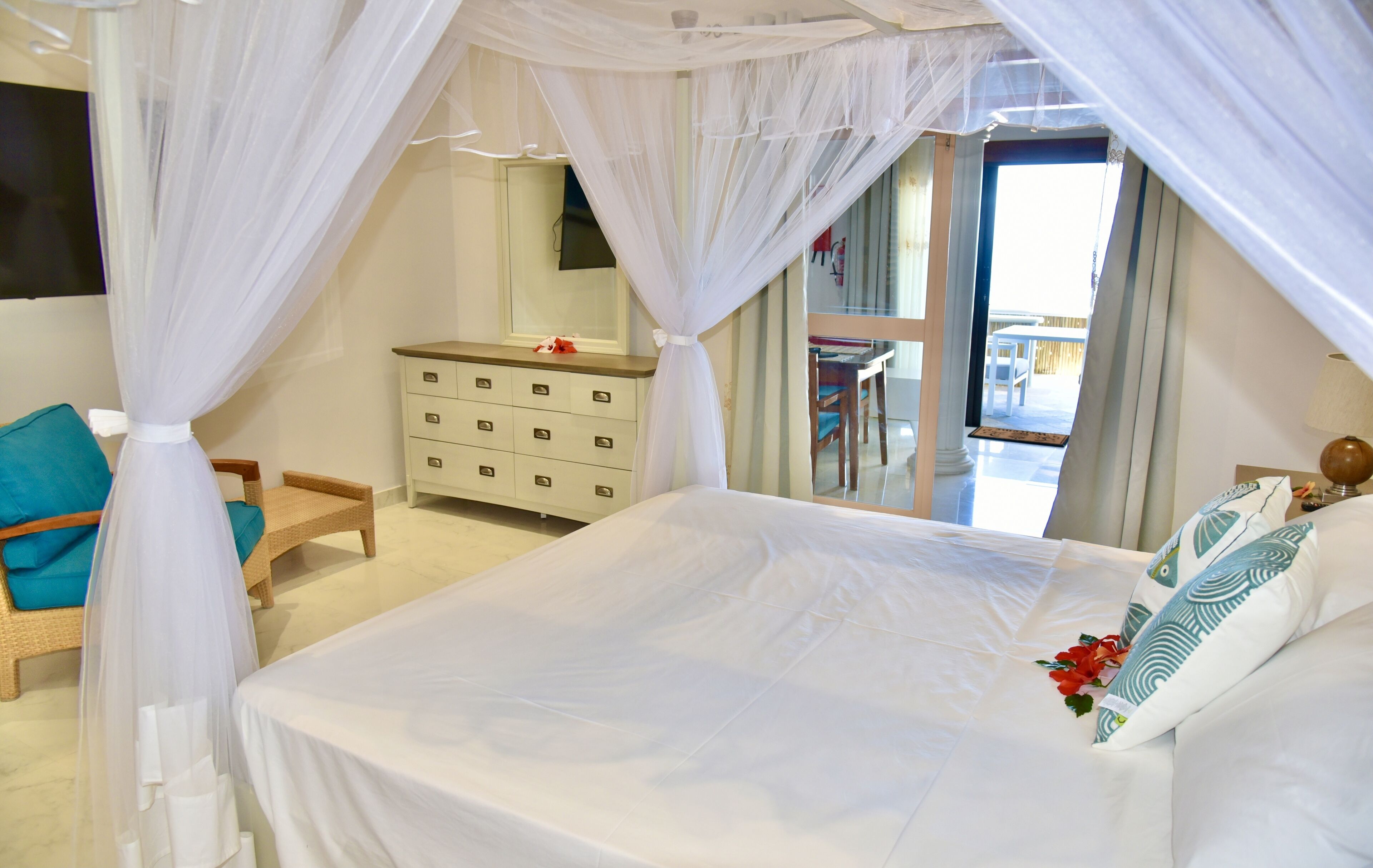 Quarto com cama de dossel, cômoda e vista para o exterior.