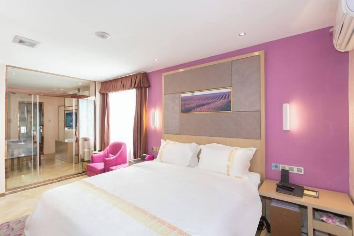 Quarto de hotel com cama, escrivaninha, cadeira e um espelho grande.