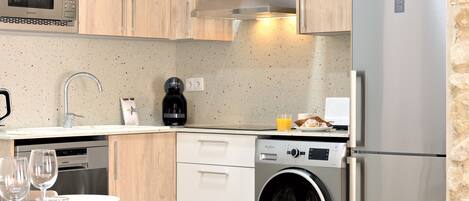 Cozinha moderna com armários de madeira, geladeira de aço inoxidável, máquina de lavar embutida e micro-ondas.