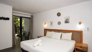 Quarto de hotel com cama, mesa de cabeceira, luminária na parede e vista para o exterior.