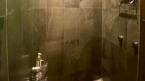 Um chuveiro moderno com porta de vidro, chuveiro manual e dispensador de sabonete.