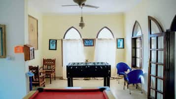 Um quarto com mesa de bilhar, mesa de futebol de mesa e duas cadeiras azuis.