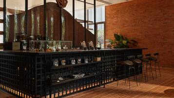 Uma área de bar moderna com parede de tijolos, janelas amplas e balcão preto com assentos.