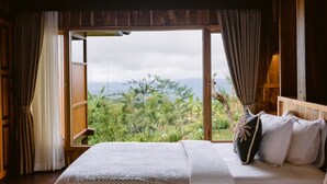 Quarto com uma janela grande, teto de madeira e uma cama com almofadas.