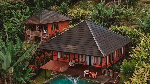 Uma casa grande com piscina, cercada por vegetação exuberante.