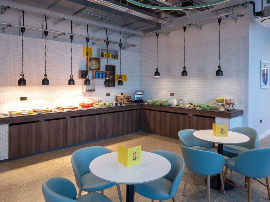 Cozinha moderna com ilha central, cadeiras azuis e iluminação pendente.