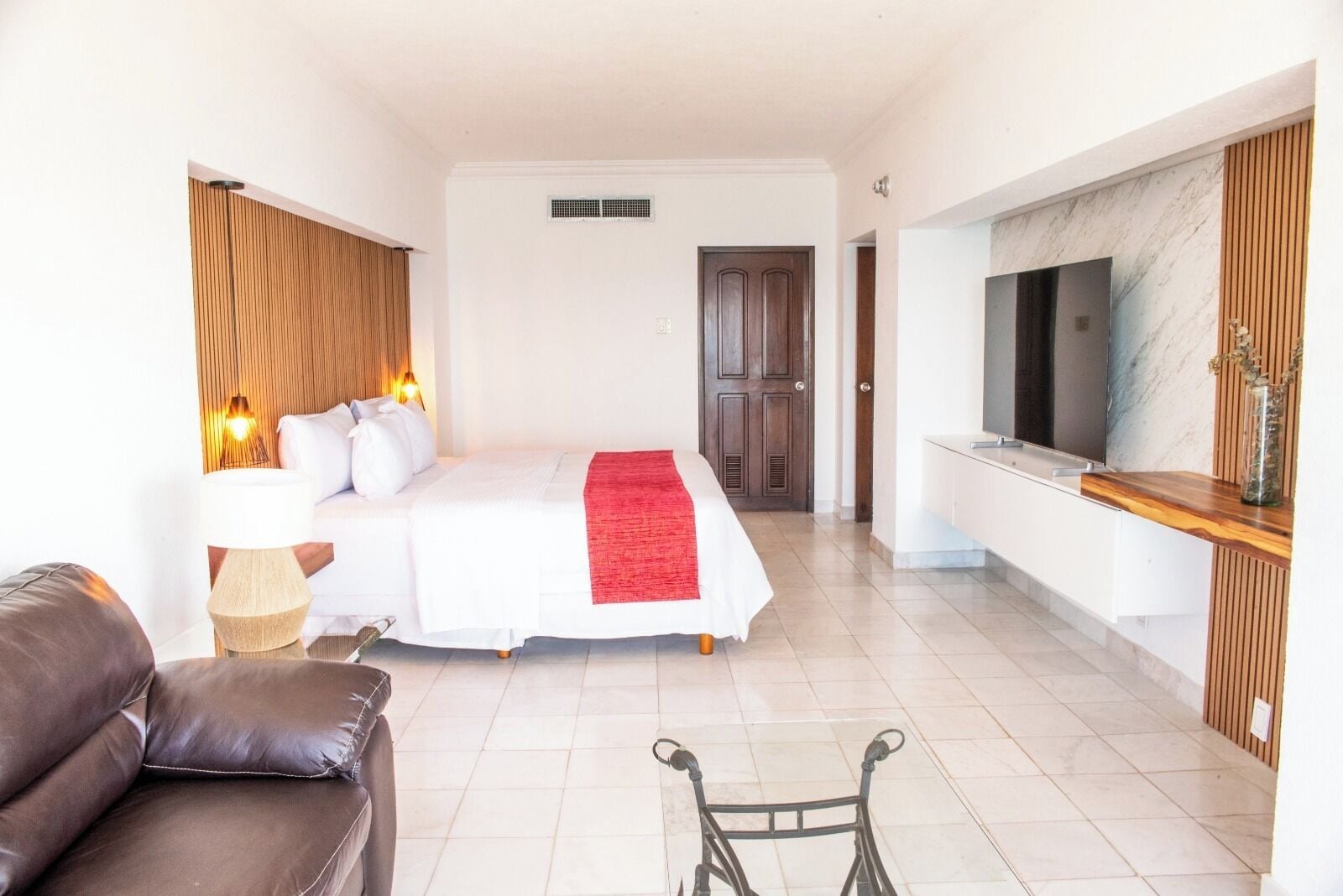 Quarto de hotel com cama, televisão, escrivaninha e cadeira.