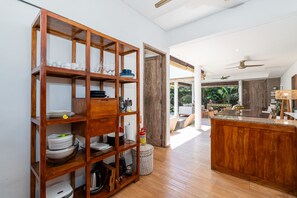 Cozinha espaçosa com prateleiras de madeira, ilha central e vista para área externa.