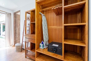 Guarda-roupa de madeira com várias prateleiras, cabideiro e um pequeno aparelho eletrónico na prateleira inferior.