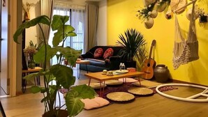 Sala de estar com uma parede amarela, um sofá preto, uma mesa de centro de madeira e uma guitarra.