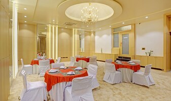 Uma sala de conferências com mesas redondas, cadeiras brancas e um lustre.