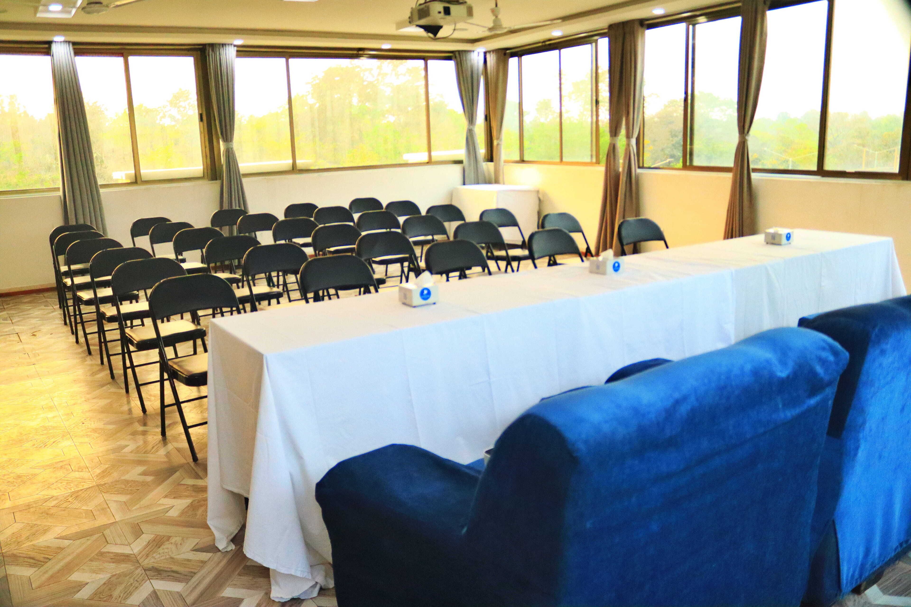 Uma sala de conferências com uma mesa comprida, cadeiras e amplas janelas.