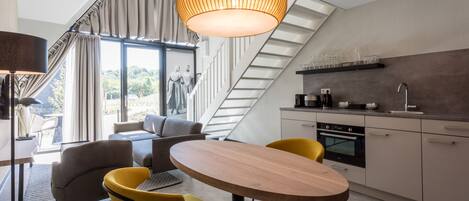 Cozinha moderna com área de jantar, destacando uma mesa de madeira, cadeiras amarelas e uma luminária pendente grande.