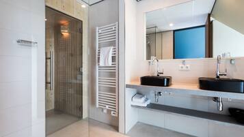 Uma casa de banho moderna com duas pias, um espelho grande e cabine de duche em vidro.