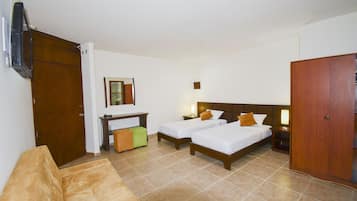 Quarto de hotel com duas camas, um sofá, uma televisão, uma escrivaninha e um guarda-roupa.