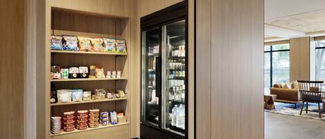 Um interior moderno com uma estante de madeira exibindo diversos alimentos e uma geladeira preta.