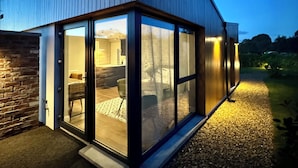 Uma casa moderna com uma grande porta de vidro que dá para uma sala de estar com sofá e mesa de centro.