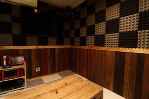 Um estúdio de gravação com painéis acústicos, uma mesa de madeira e equipamentos de áudio.