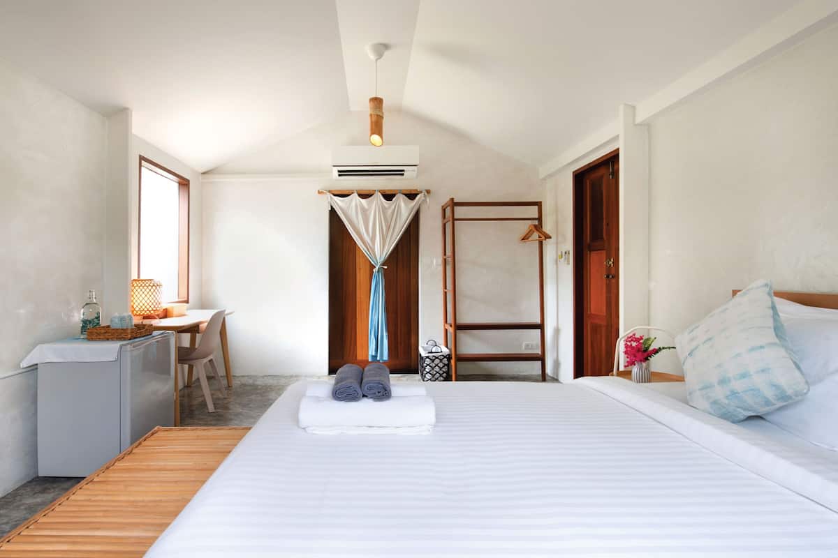 Quarto de hotel pequeno com cama, escrivaninha e cadeira.