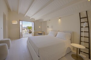 Quarto amplo com cama grande, escrivaninha e vista para o exterior.