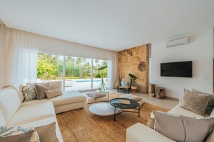 Uma sala de estar moderna com uma janela grande, televisão de tela plana e uma parede de destaque em pedra.