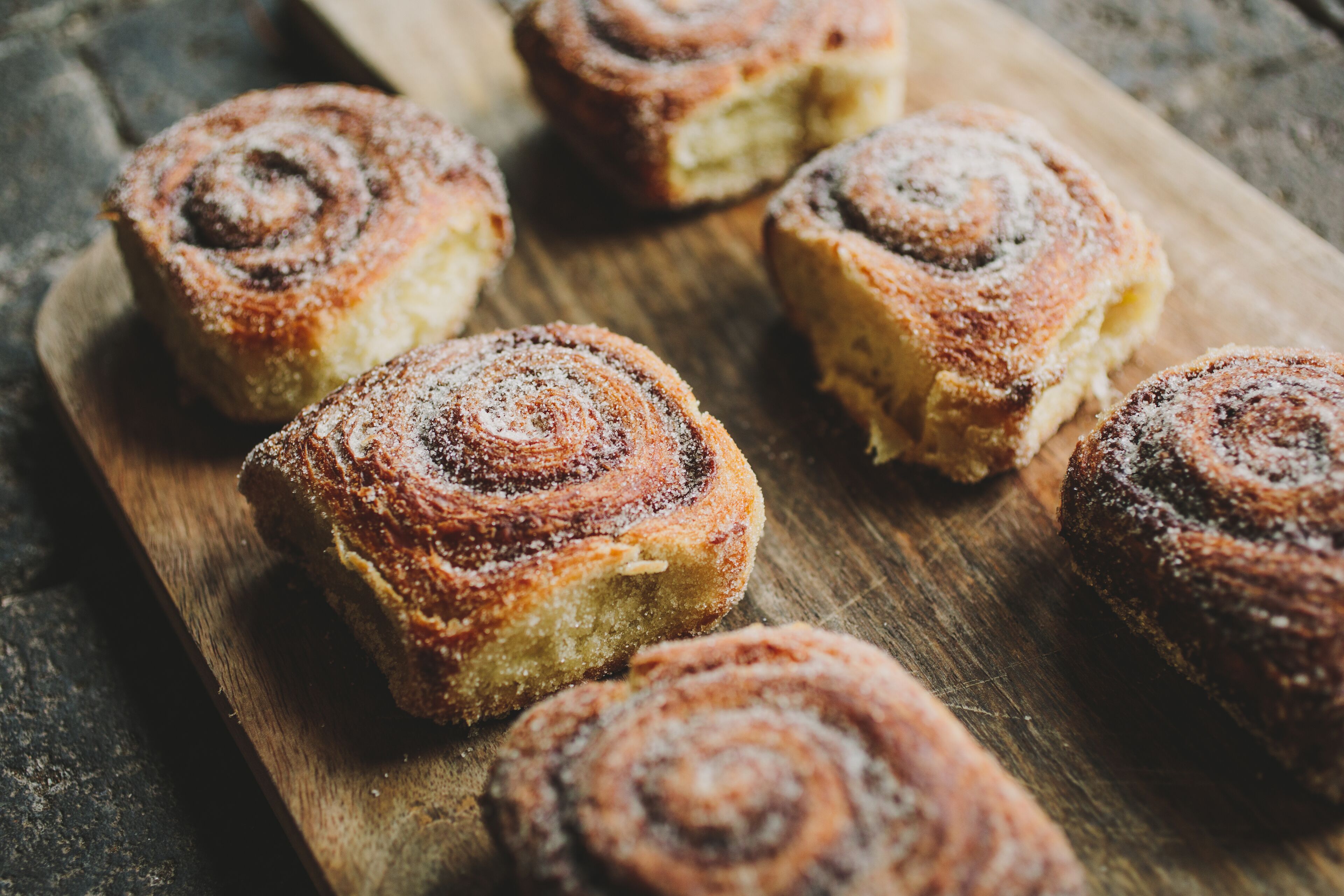 Uma tábua de madeira com vários cinnamon rolls.