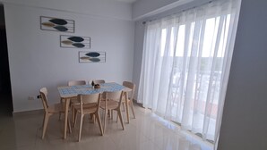 Uma área de refeições com mesa e cadeiras, uma janela com cortinas leves e obras de arte nas paredes.