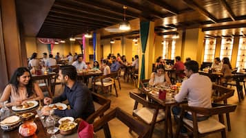 Restaurante com mesas e cadeiras de madeira, clientes jantando e ambiente acolhedor.