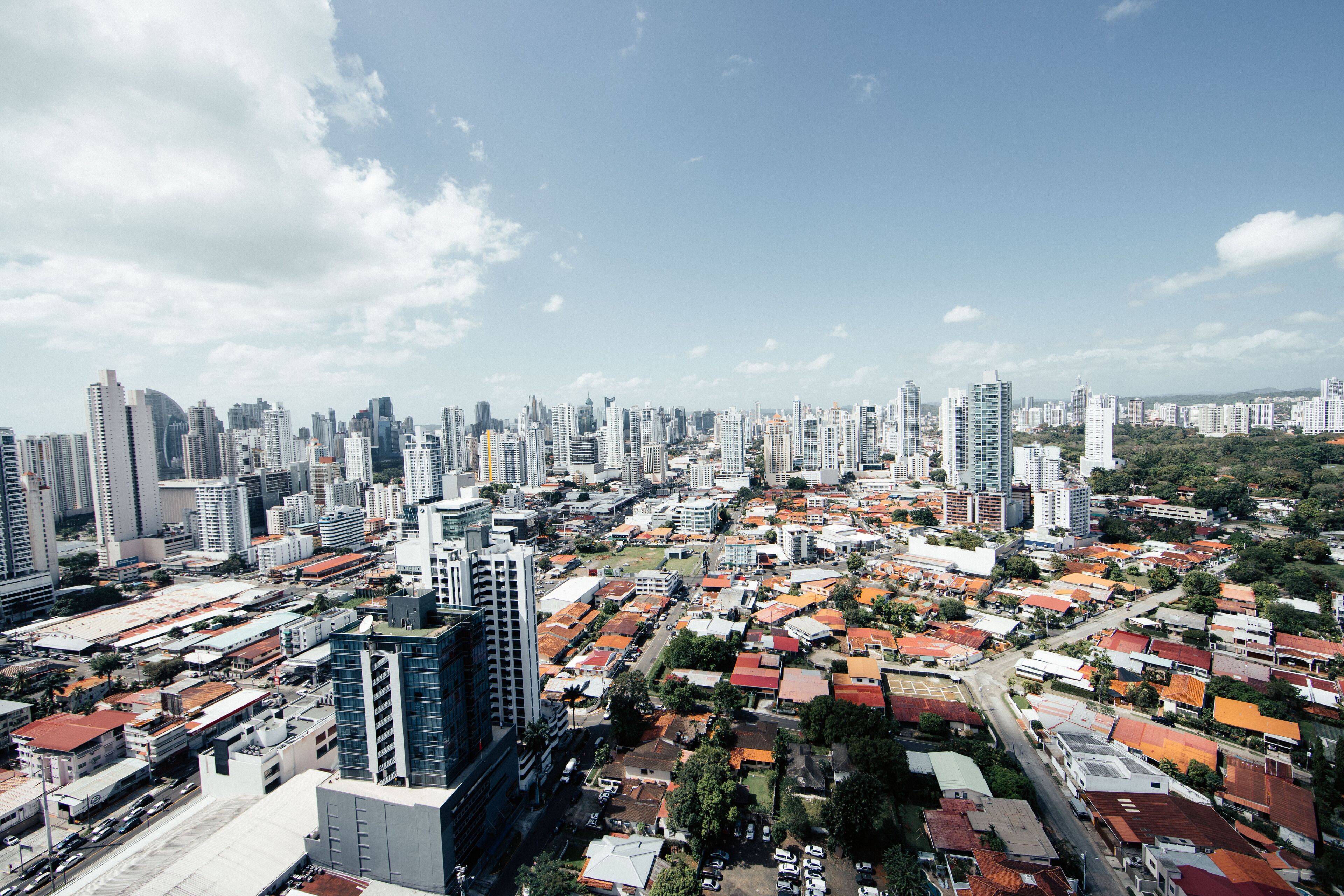 Vista aérea de um horizonte urbano com edifícios altos, uma combinação de construções residenciais e comerciais, e um céu claro.