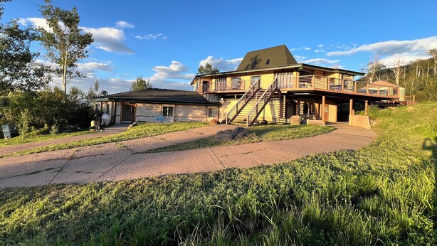 Uma casa de dois andares com varanda frontal grande e escada que leva ao andar superior.