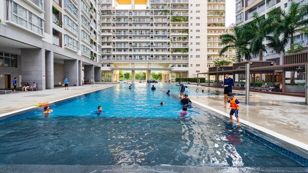Uma área de piscina com vários níveis de varandas, um amplo espaço aberto e fachada de um edifício moderno.