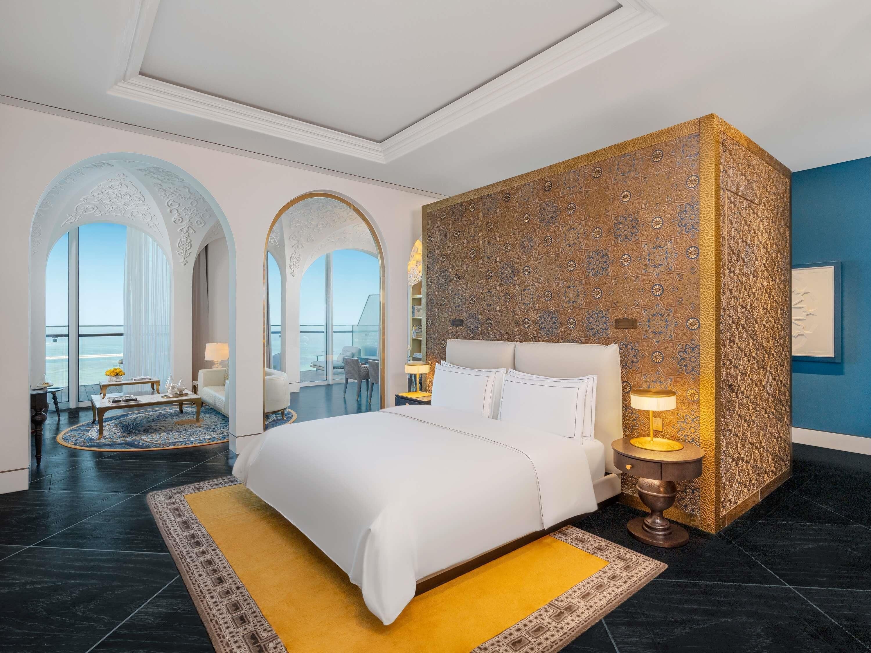 Quarto de hotel moderno com uma cama grande, uma varanda e uma vista, e uma parede decorativa.