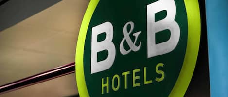 Um close-up do letreiro da B&B Hotels, com um esquema de cores verde e amarelo.