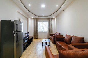 Um espaço compacto com cozinha compacta, um sofá de couro marrom, uma mesa pequena e uma janela com cortinas.