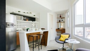 Cozinha compacta com ilha central, banquetes e pequena mesa de jantar.
