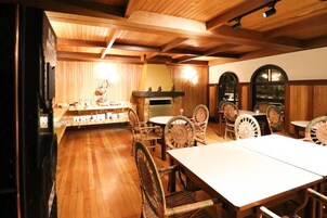 Um restaurante com pisos e paredes de madeira, cadeiras de vime e uma mesa central.