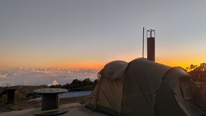 Uma tenda montada num terraço com vista ampla da paisagem abaixo.