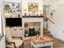 Uma sala de estar aconchegante com lareira, televisão, poltrona confortável e mesa de centro.