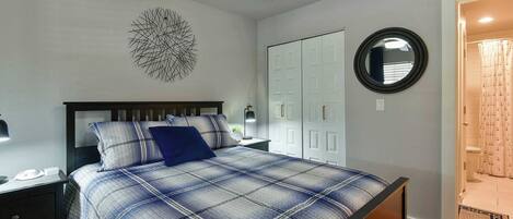 Quarto com cama, mesa de cabeceira, decoração na parede, guarda-roupa e ventilador de teto.